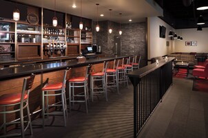Uma área de bar com vários bancos, balcão e um espaço de estar com sofás.