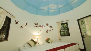 Quarto com cama, abajur e decoração de pássaros em um galho.