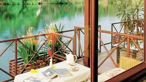 Quarto com vista para um lago, uma mesa com chaleira e uma cadeira.