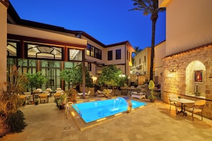 Uma área junto à piscina com mobiliário externo, piscina e um muro de pedra com um mural.