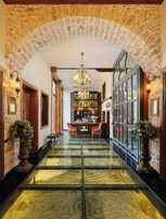 Um amplo salão com piso de vidro, portas de madeira e um candelabro.