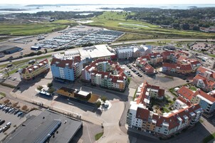 Vista aérea de uma área residencial com edifícios de apartamentos, um estacionamento e um campo de golfe ao fundo.