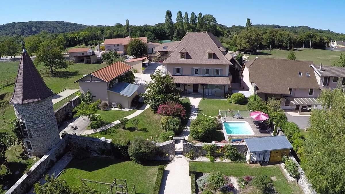 Uma extensa propriedade com vários edifícios, piscina e uma torre de pedra.