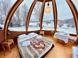 Um quarto aconchegante e circular com uma cama, uma mesa pequena e um lustre.