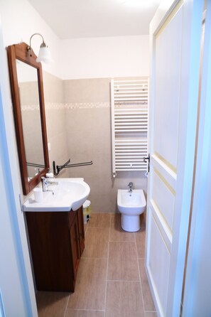 Casa de banho com lavatório, espelho e sanita.