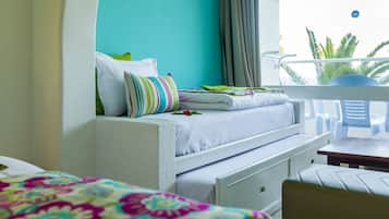 Quarto com cama, uma mesinha e vista para palmeiras.
