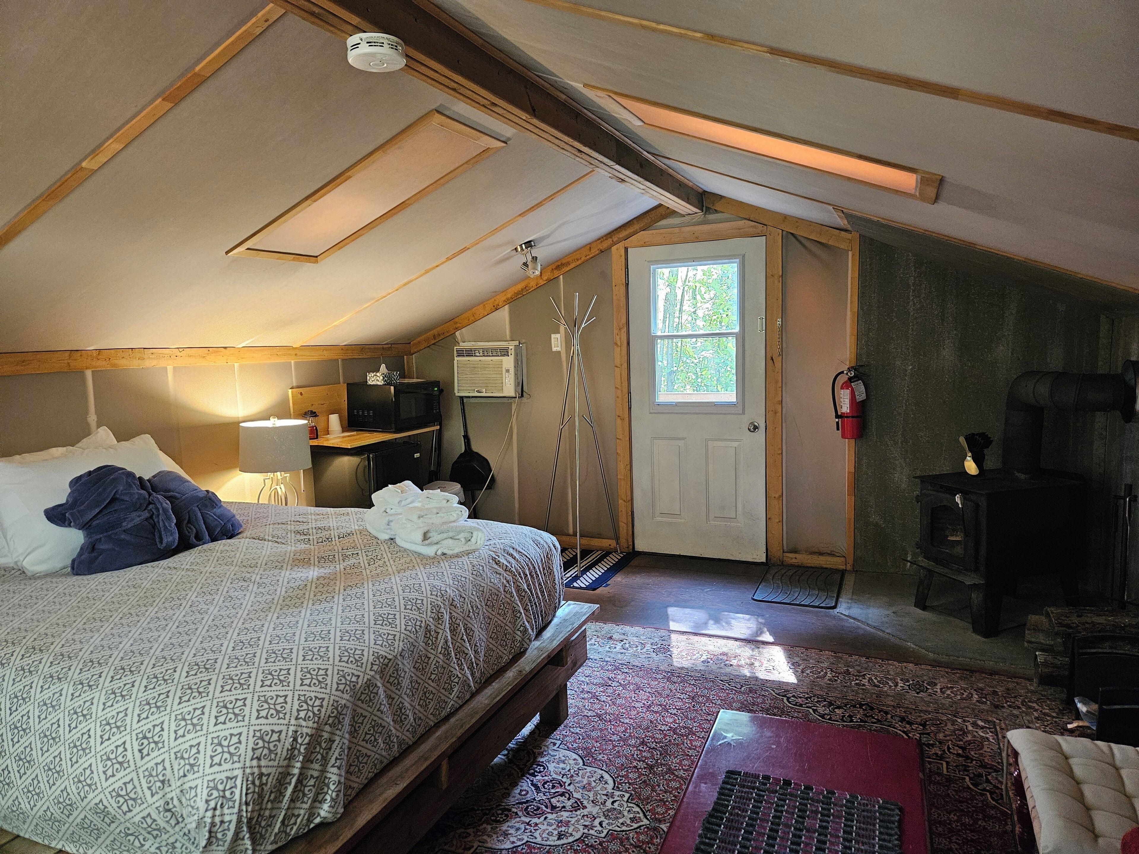 Um quarto de sótão aconchegante com cama, aquecedor, janela e lareira.