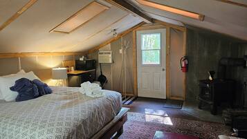 Um quarto de sótão aconchegante com cama, aquecedor, janela e lareira.