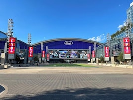 Um estádio grande com um logotipo Ford bem visível e várias telas digitais grandes.