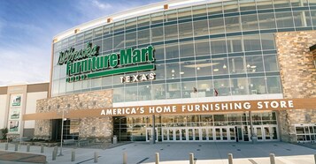 Uma loja de móveis com uma fachada de vidro ampla e uma placa com a inscrição 'Nebraska Furniture Mart Texas'.