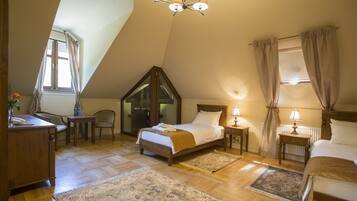 Quarto com teto inclinado, cama de madeira, duas mesas de cabeceira com abajures, uma cadeira, escrivaninha e janela com cortinas.