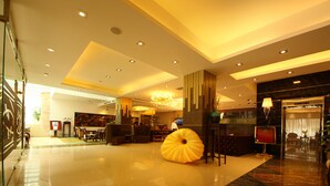 Um amplo hall com uma grande escultura de guarda-chuva amarelo, um lustre e um balcão de recepção moderno.