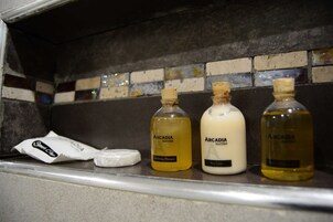 Uma prateleira no banheiro com três frascos de shampoo e um sabonete.