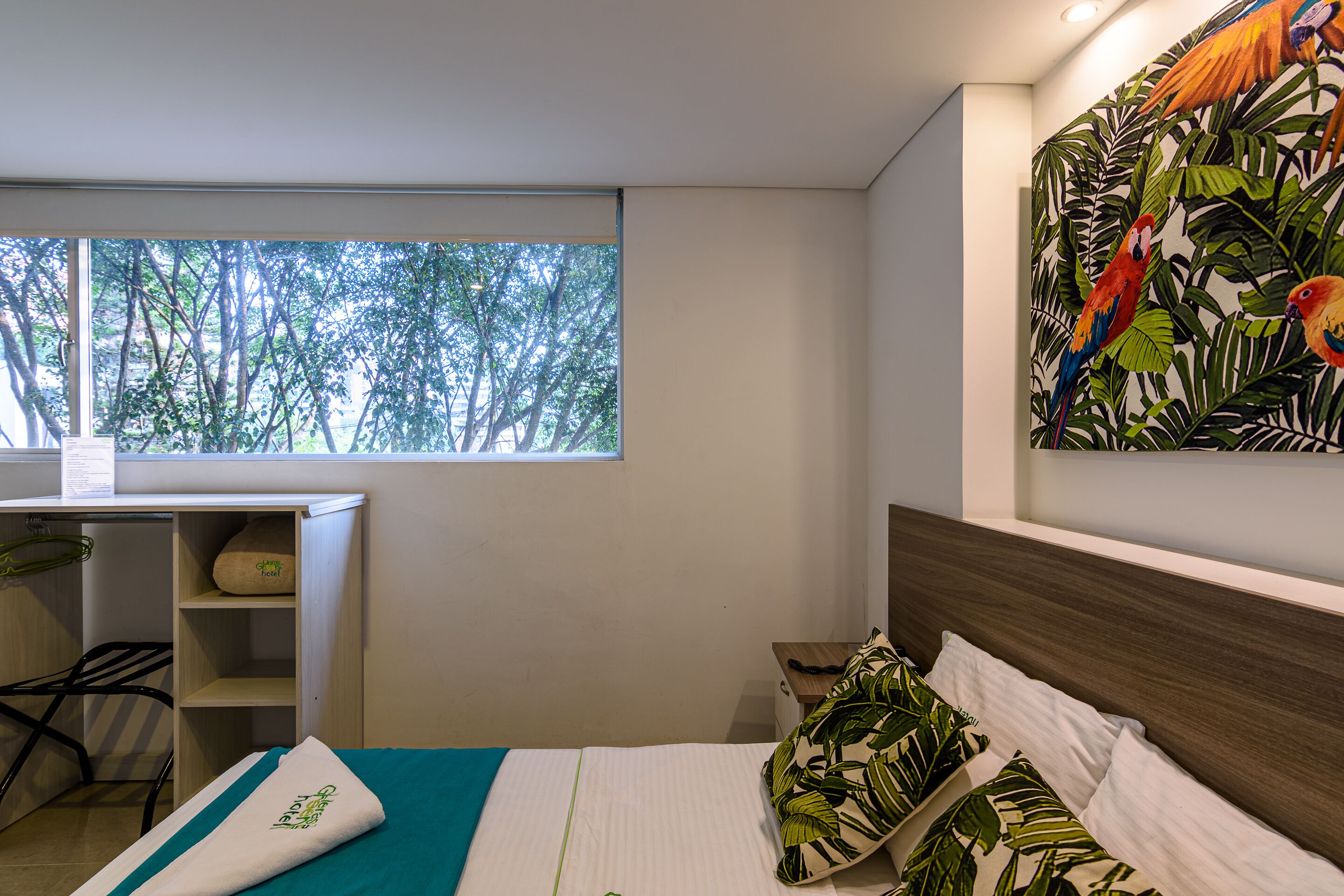 Quarto com cama, escrivaninha e janela com vista para árvores.