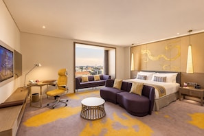 Quarto de hotel com cama, sofá, escrivaninha e cadeira.