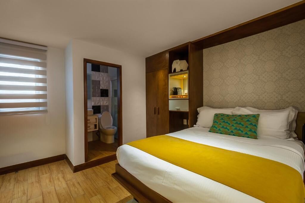Quarto de hotel com cama, banheiro e uma pequena cozinha.