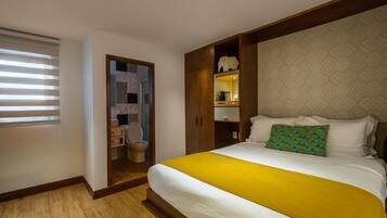 Quarto de hotel com cama, banheiro e uma pequena cozinha.