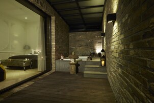 Uma área de spa com um deck de madeira, uma fonte de pedra e uma banheira.