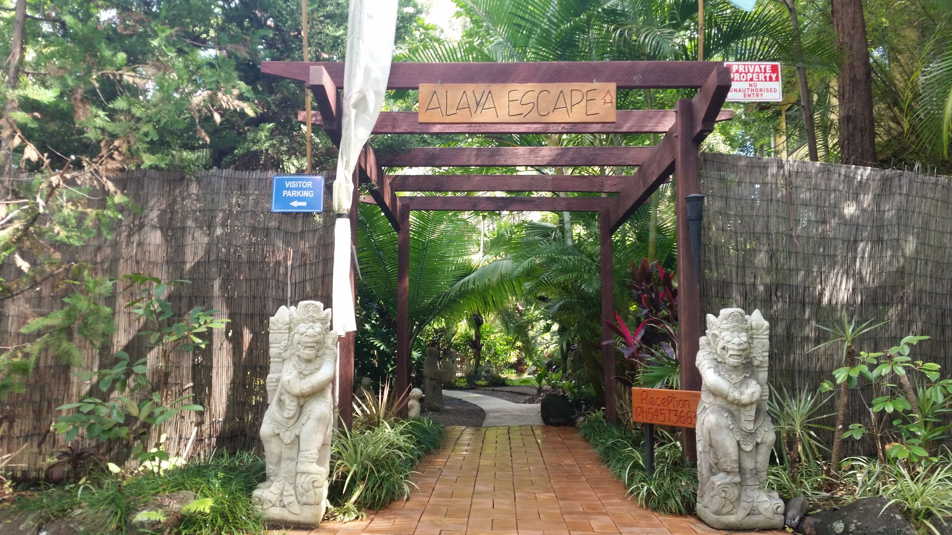 Um arco de madeira com uma placa que diz "ALAYA ESCAPE" e uma placa com a inscrição "PROPRIEDADE PARTICULAR, PROIBIDA ENTRADA NÃO AUTORIZADA".