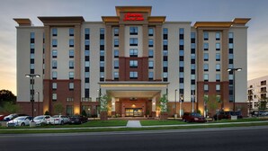 Um hotel de vários andares com uma placa chamativa que diz 'Hampton Inn & Suites'.