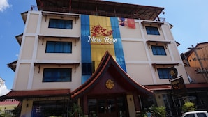 Um hotel chamado "New Rose", com uma placa bem visível, várias janelas e estilo arquitetônico tradicional.