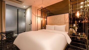 Quarto de hotel moderno com uma cama grande, divisória de vidro e piso de mármore.