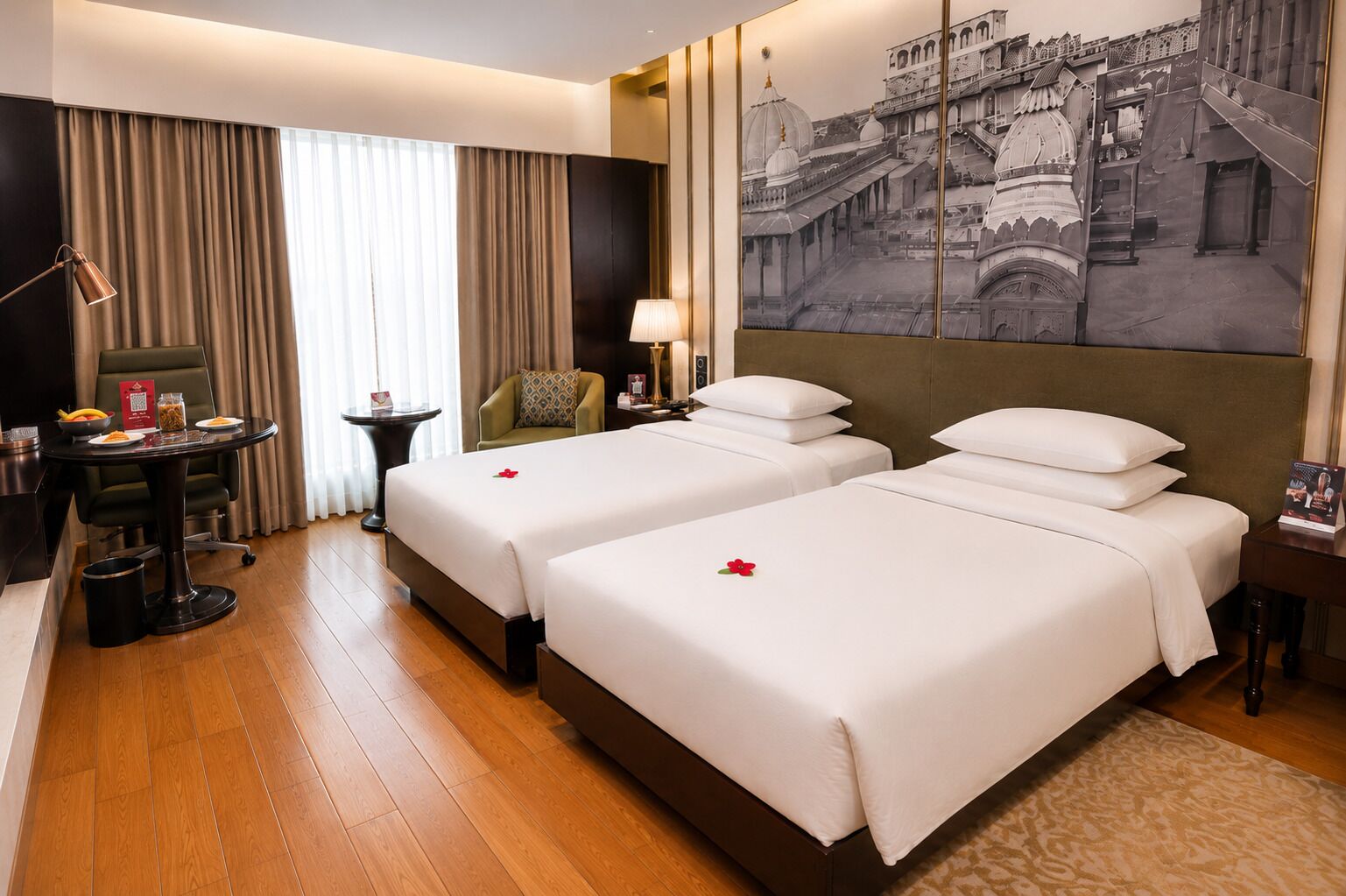 Quarto de hotel com duas camas, uma escrivaninha, uma cadeira, um abajur e um quadro grande na parede.