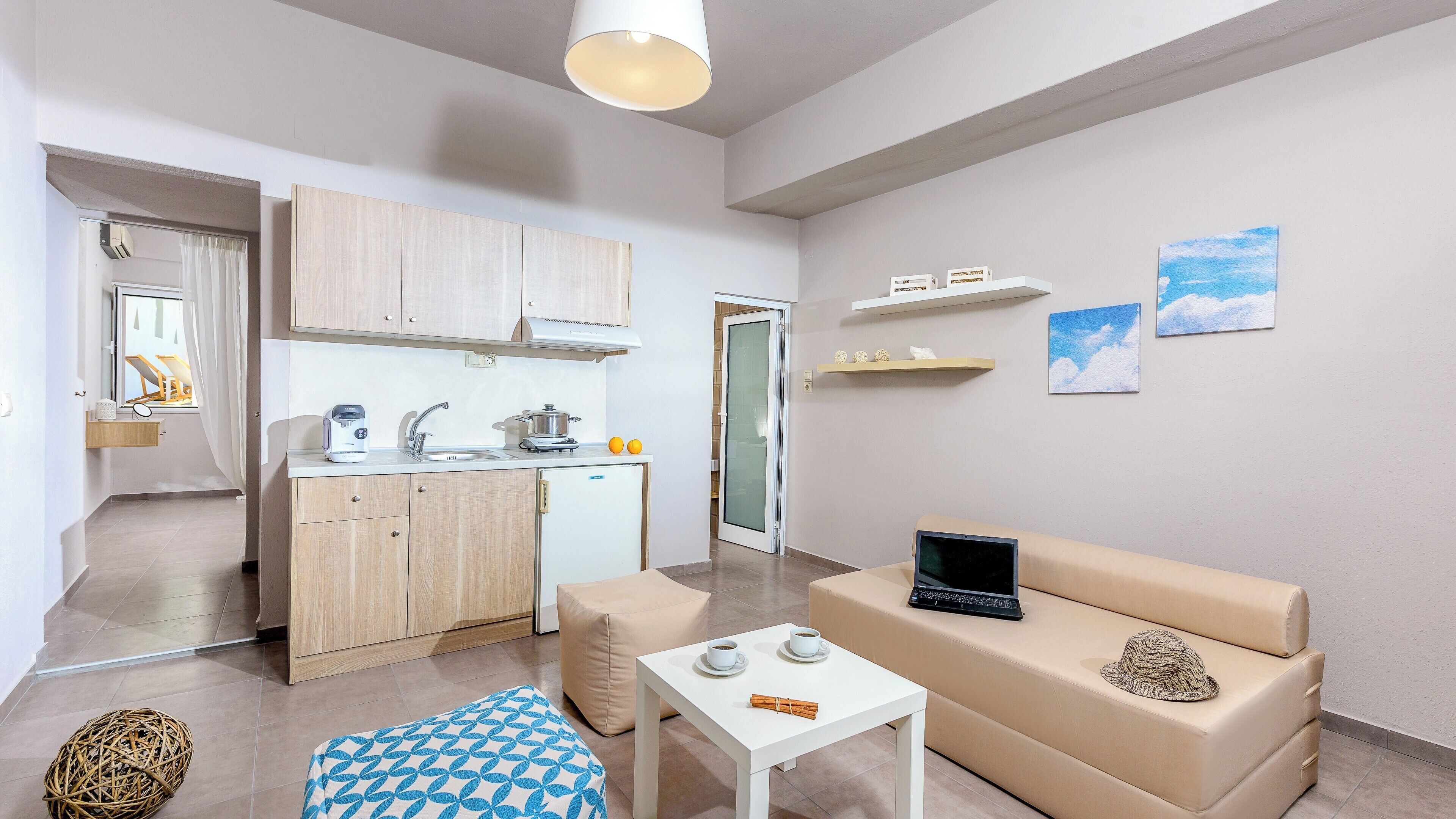 Um espaço compacto com cozinha compacta, sofá, mesa de centro e um laptop.