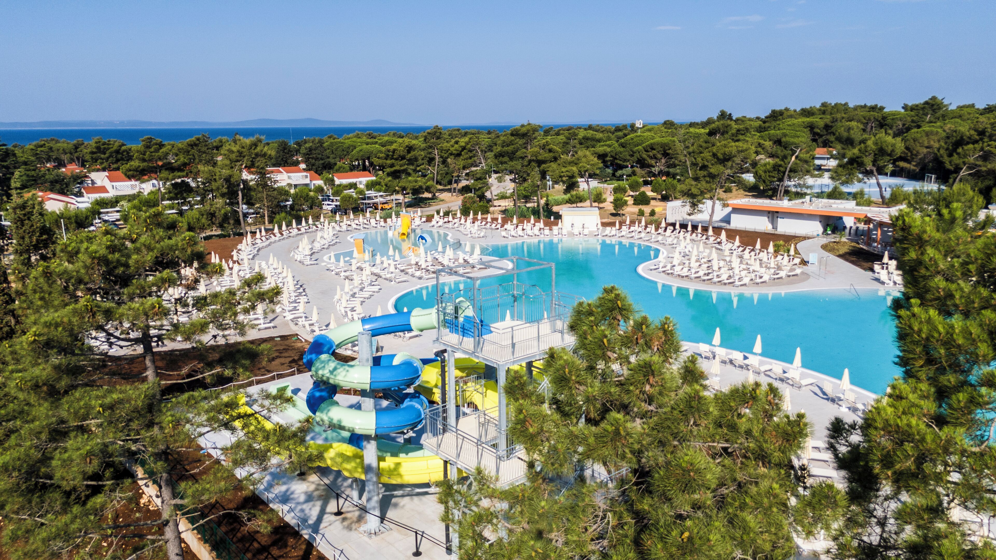 Um resort com uma piscina grande, toboáguas e vista para o mar.