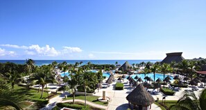 Um resort com várias piscinas, palmeiras e vista para o oceano.