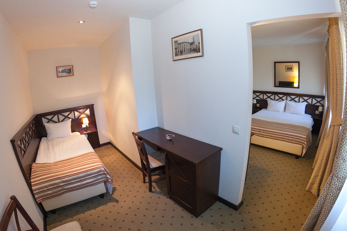 Quarto de hotel com duas camas, uma escrivaninha e uma cadeira.