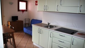 Cozinha compacta com pia, armários e área de jantar com mesa e cadeiras.
