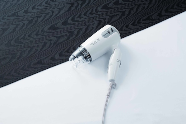 Secador de cabelo branco com fio sobre superfície branca.