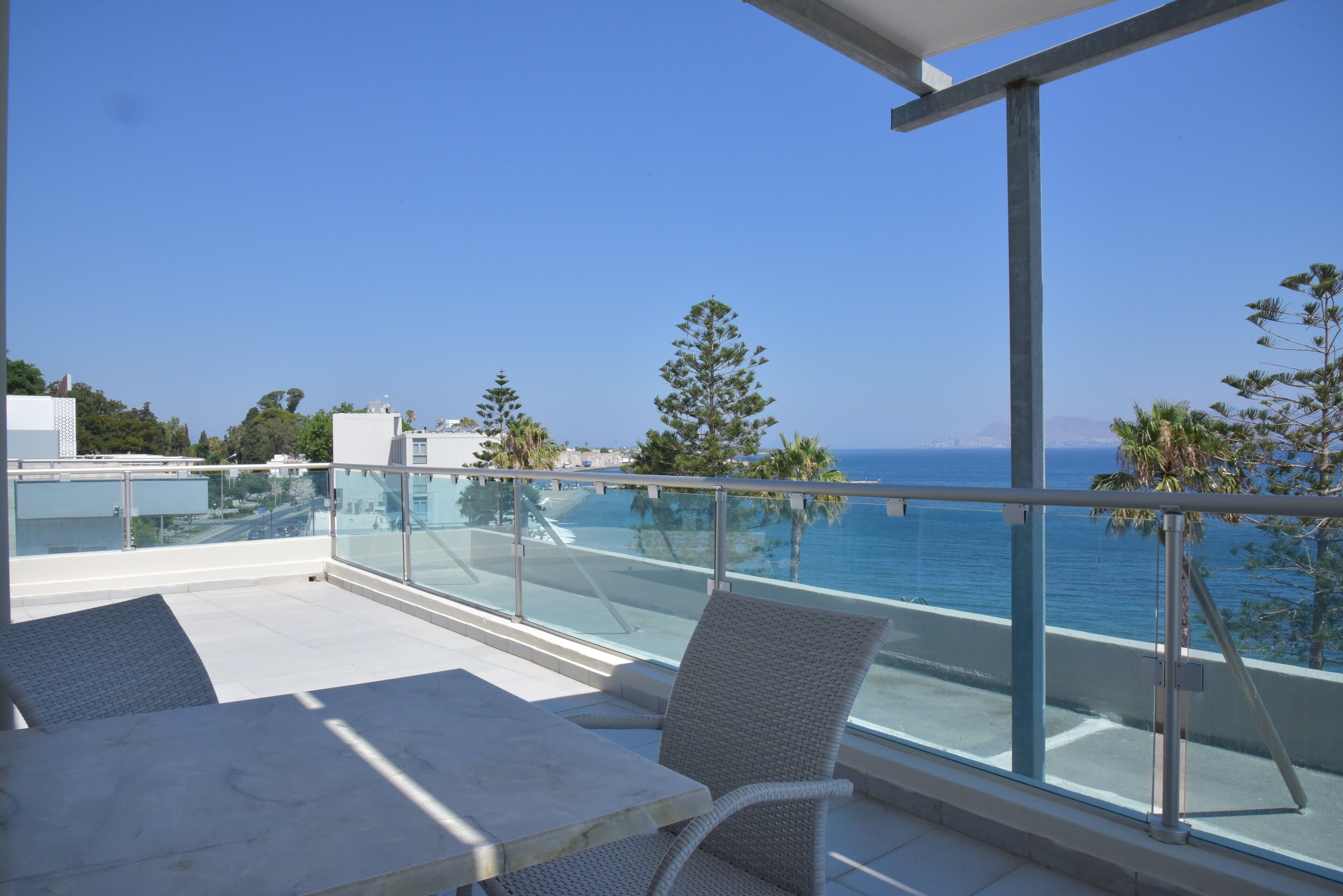 Varanda com guarda-corpo de vidro, vista para a piscina e oceano.