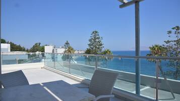 Varanda com guarda-corpo de vidro, vista para a piscina e oceano.