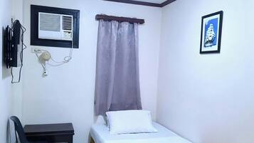 Quarto pequeno e bem arrumado, com uma cama, escrivaninha e uma cadeira.