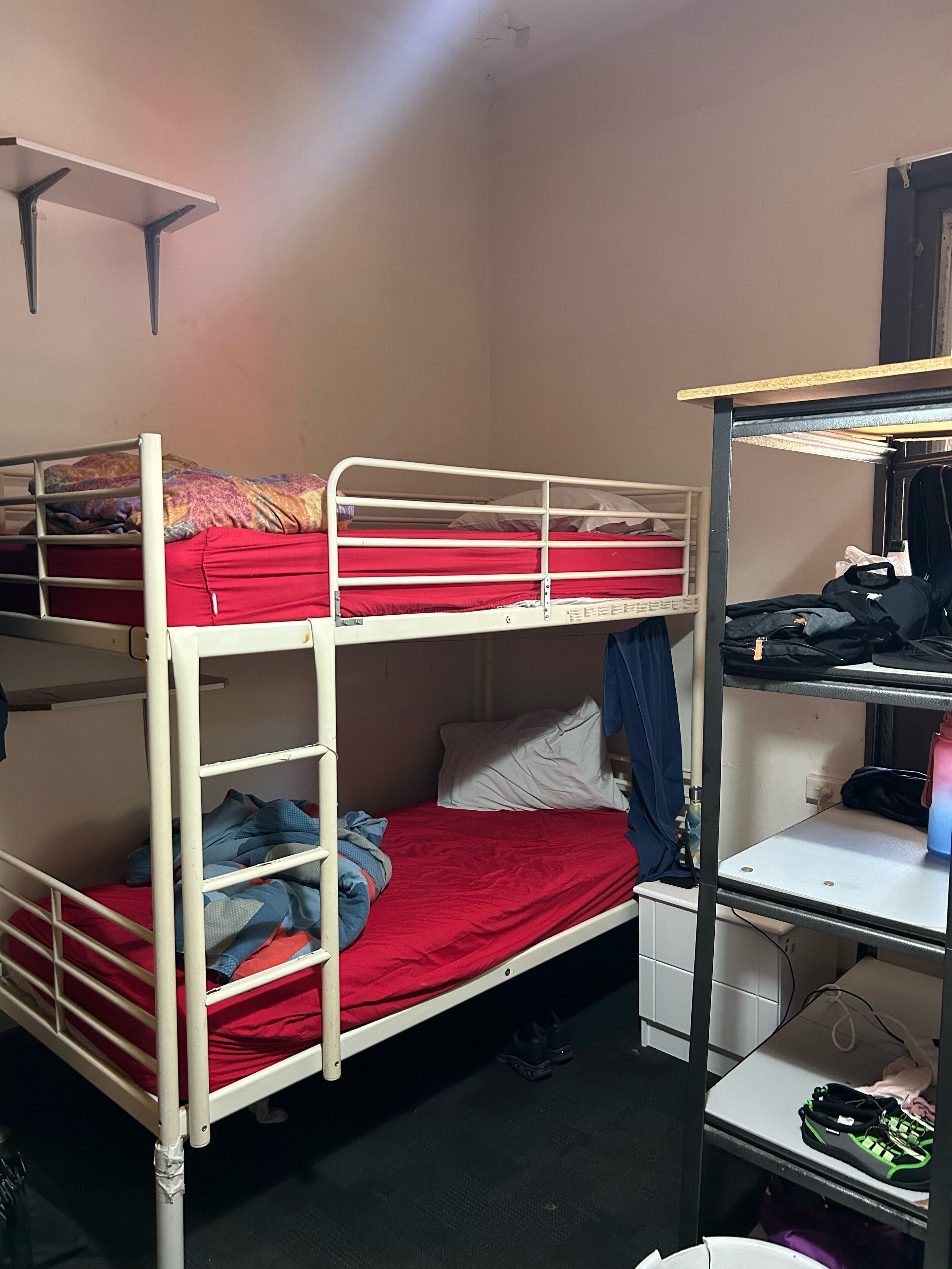 Quarto com beliche e estante com roupas e sapatos.