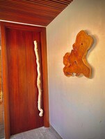 Uma porta de madeira com maçaneta entalhada e uma escultura de madeira fixada na parede.