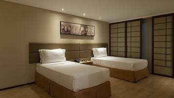 Quarto de hotel com duas camas, uma janela ampla com vista e um quadro na parede.
