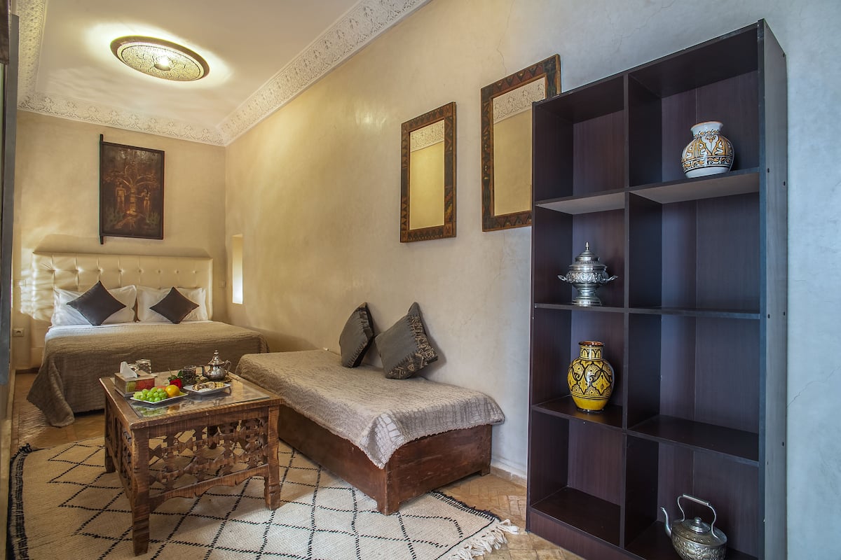 Quarto com cama, mesa de cabeceira e estante de livros.