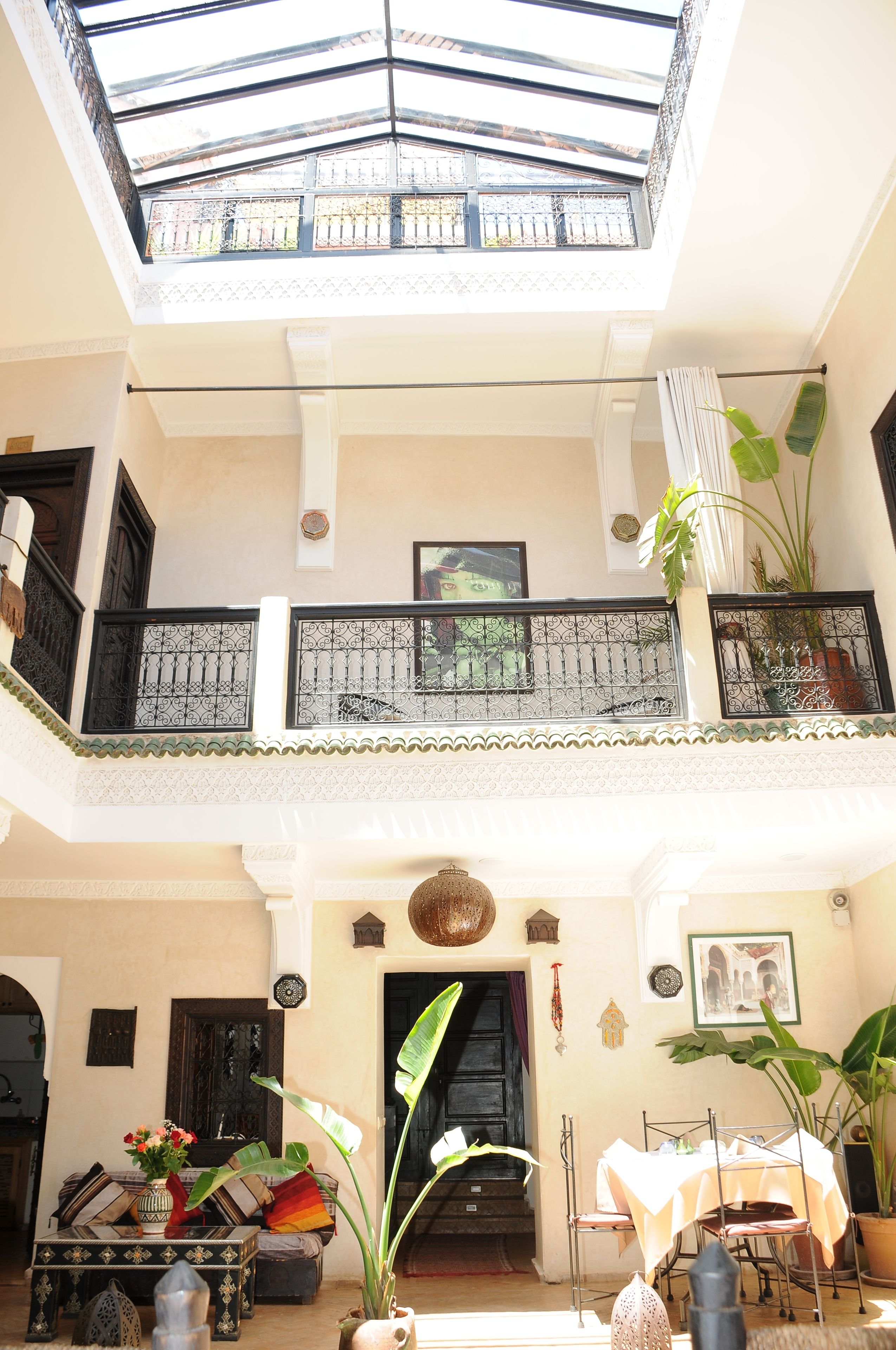 Interior em vários níveis com uma escadaria central, uma varanda com guarda-corpo e diversas plantas.