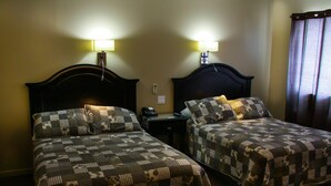Quarto de hotel com duas camas, cada uma com colcha acolchoada e almofadas a combinar. Há luminárias de cabeceira e um telefone na mesa de cabeceira.