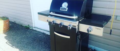 Uma churrasqueira Cuisinart para áreas externas, com quatro queimadores, um queimador lateral e um compartimento de armazenamento.