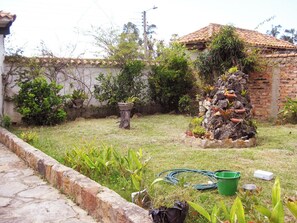 Um jardim com muro de pedra, plantas em vasos e um edifício de tijolos.
