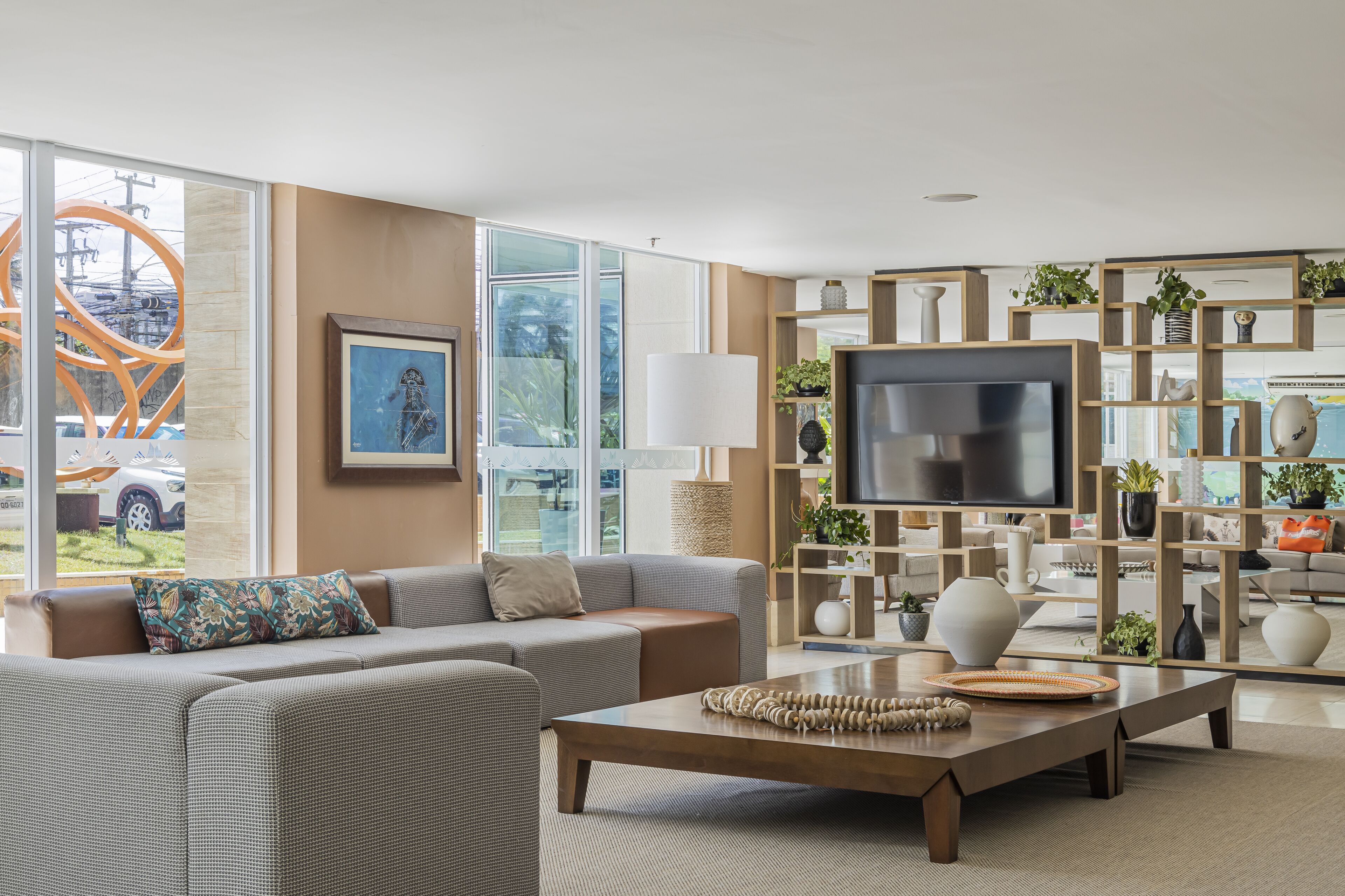 Uma sala de estar moderna com sofá, mesa de centro, televisão e prateleiras decorativas.