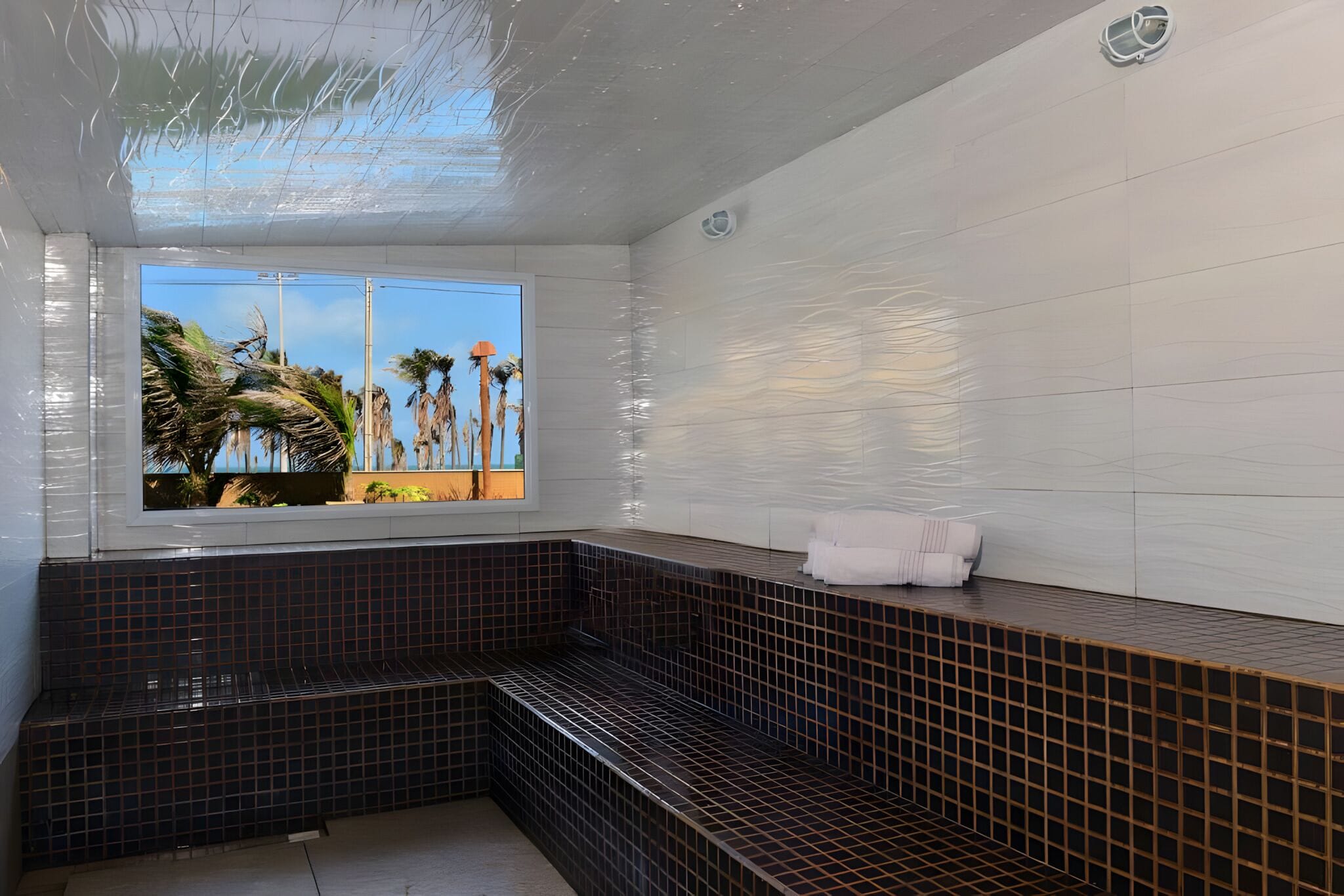 Um quarto de spa com vista para palmeiras, uma janela e um banco de azulejos.