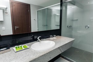 Um banheiro moderno com bancada de granito, pia branca e box de vidro.