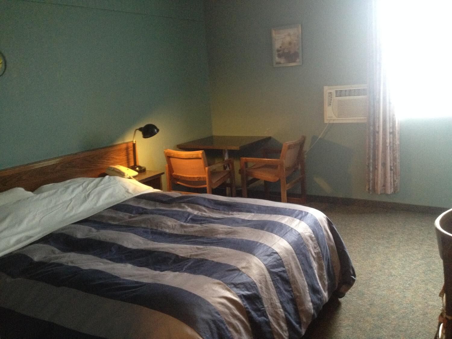 Quarto de hotel com cama, escrivaninha e cadeira.