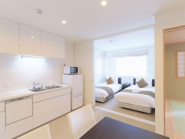 Quarto de hotel compacto com cozinha compacta, duas camas e banheiro pequeno.