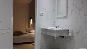 Um banheiro com pia de mármore, espelho e vaso sanitário.